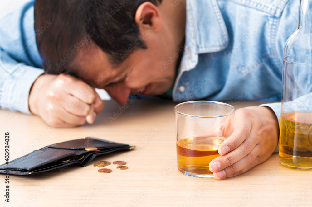 Upset young man drinker alcoholic sitting at bar counter with glass ...