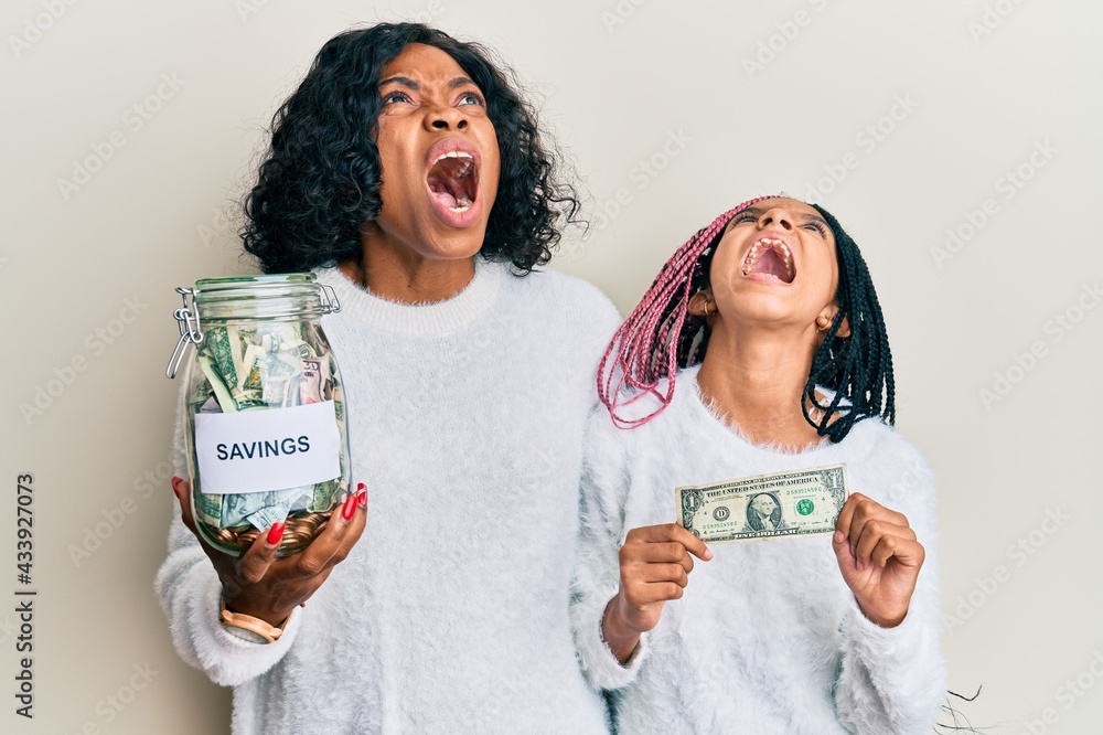 Beautiful african american mother and daughter holding jar with savings ...