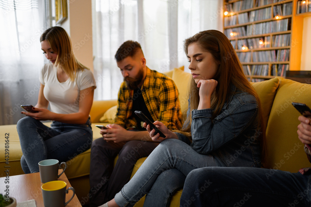Friends hanging out on a house party while using smartphones and ...
