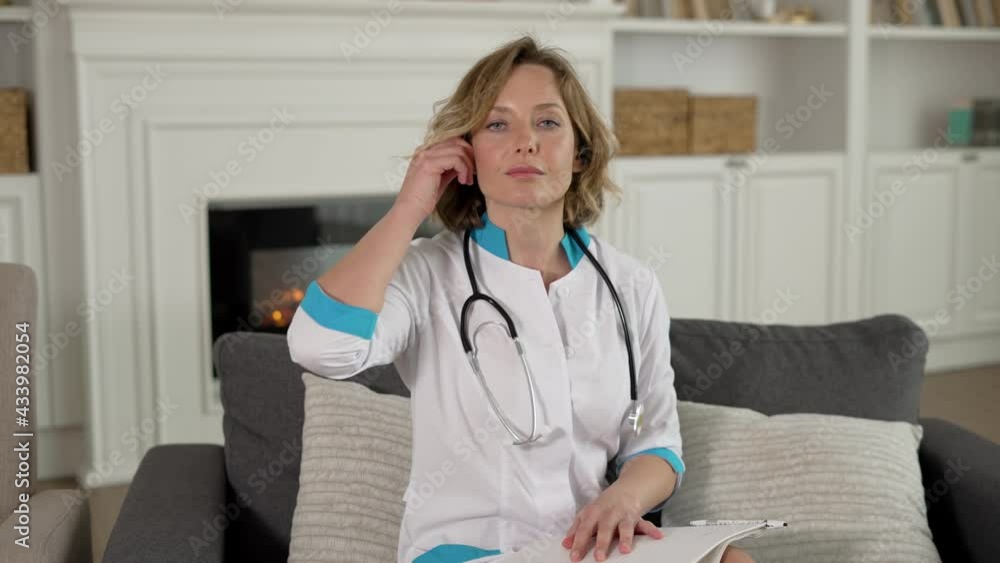 Smiling woman doctor with stethoscope on shoulders wearing wireless ...