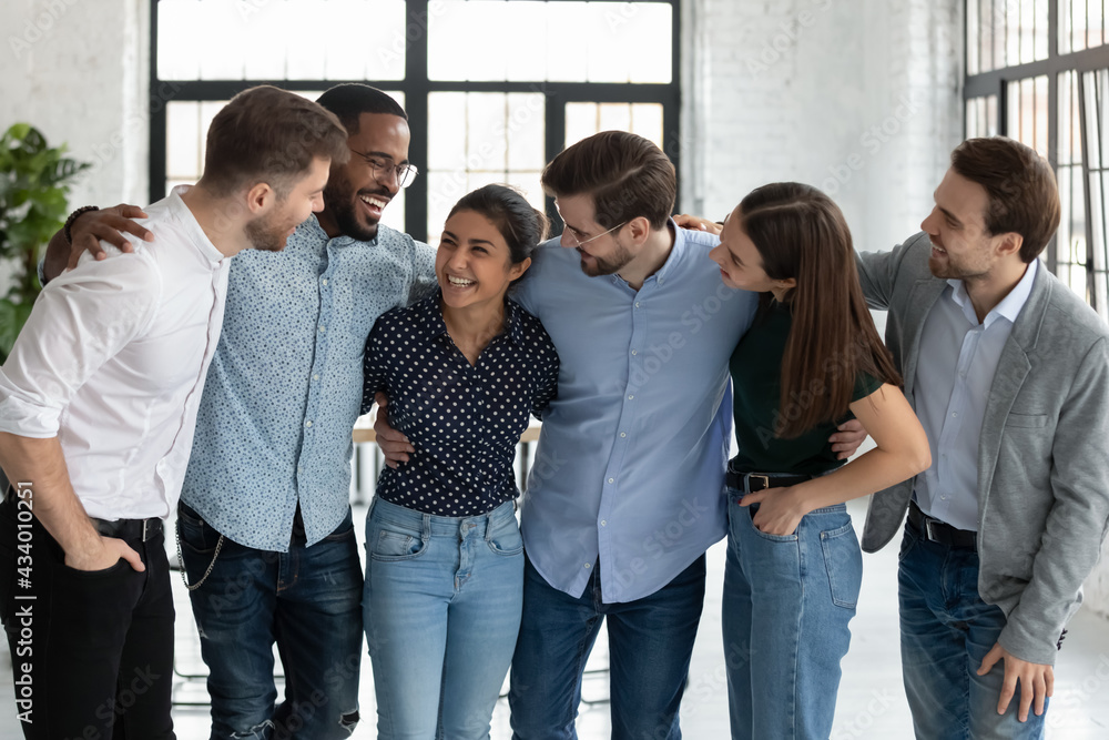 Excited diverse group of employees hugging, laughing, celebrating high ...