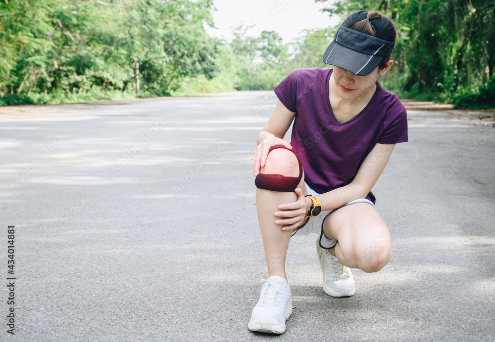 Runner woman holding her knee while she having suffering from knee pain ...
