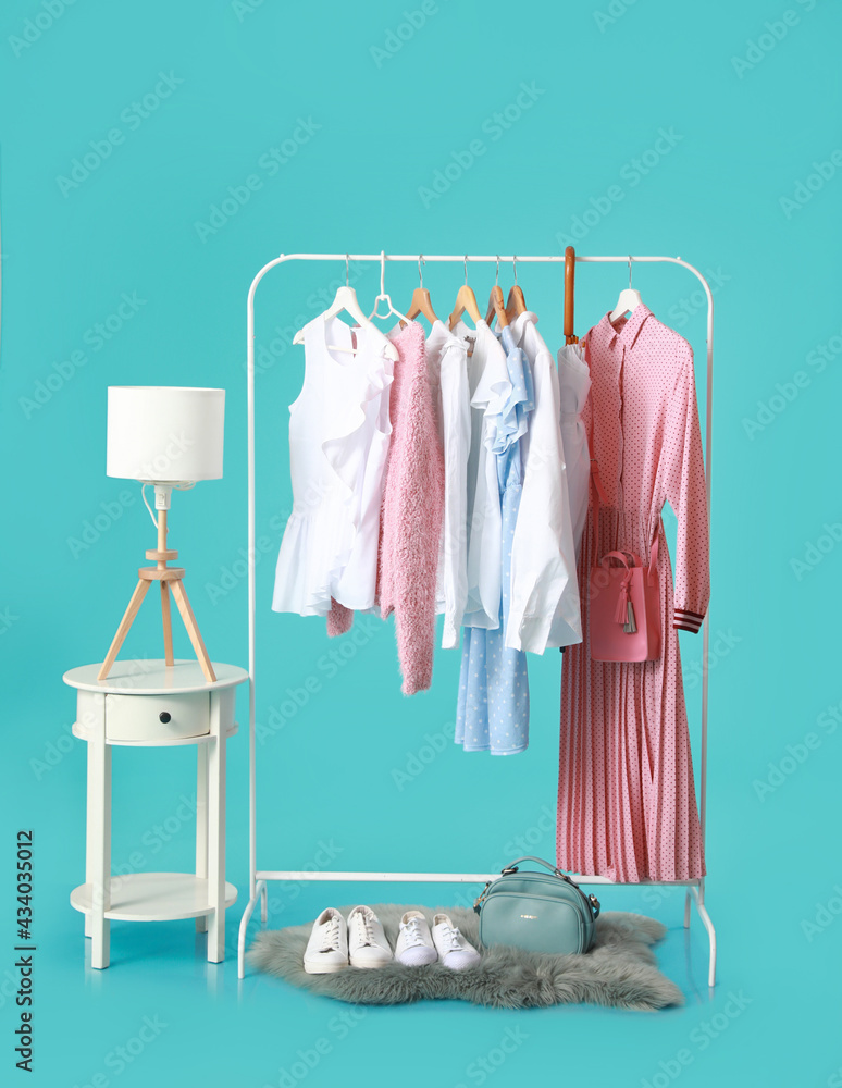 Rack with stylish clothes, accessories and table on color background ...