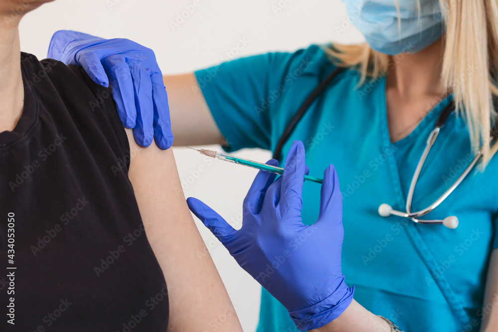 Female doctor or nurse giving shot or vaccine to a patient's shoulder ...