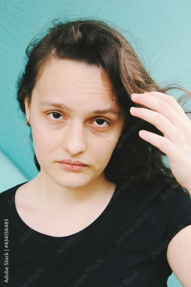 serious portrait of fair skin young womans face with blue background ...