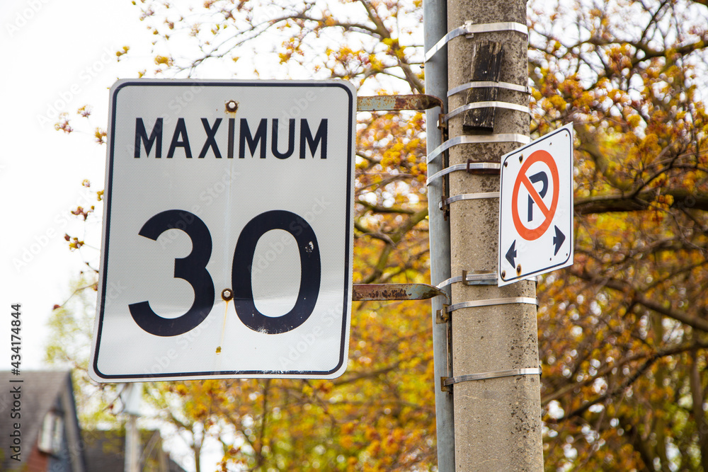 Foto de 30 Speed Limit Sign and No Parking Sign against autumn trees ...