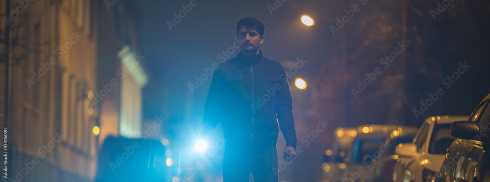 The man with a flashlight stand on the street. Evening night time Stock ...