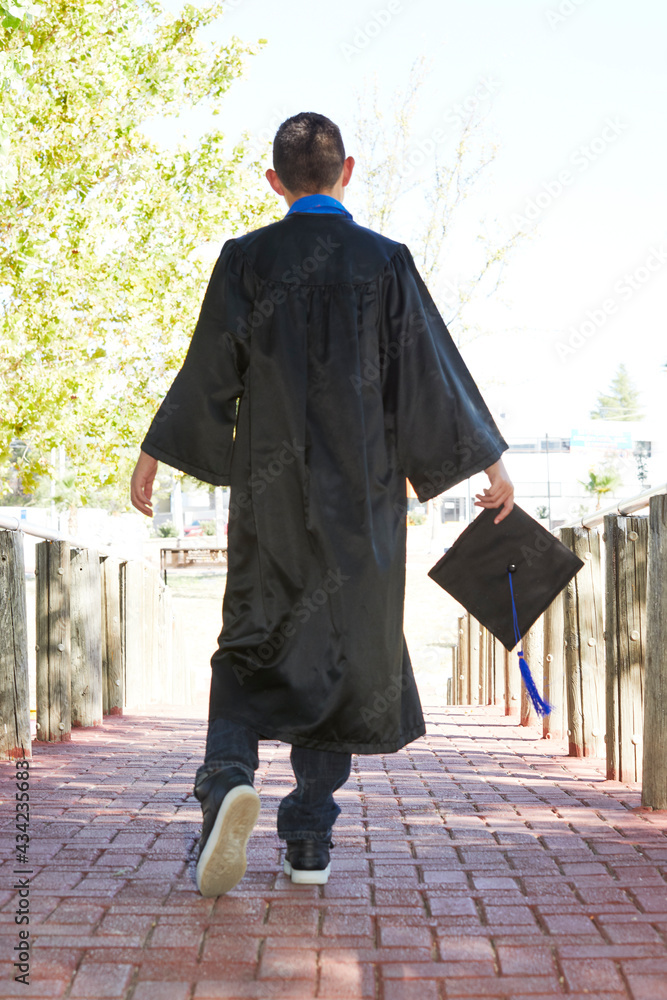 Young student celebrating his graduation, on his back with his gown and ...