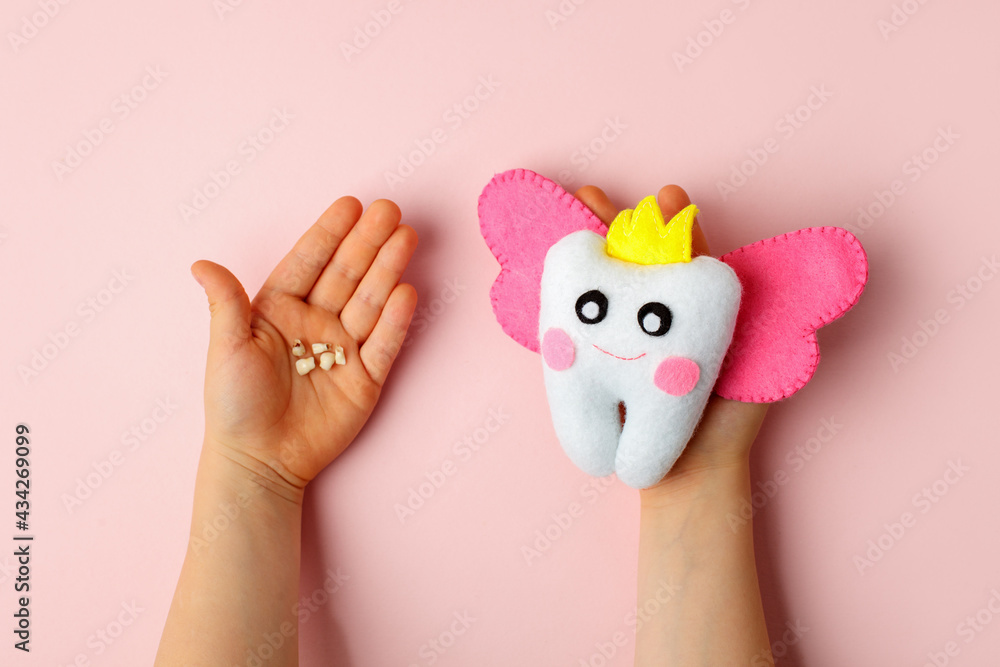 Felt tooth fairy pillow and milk tooth in kids hands on pink background ...