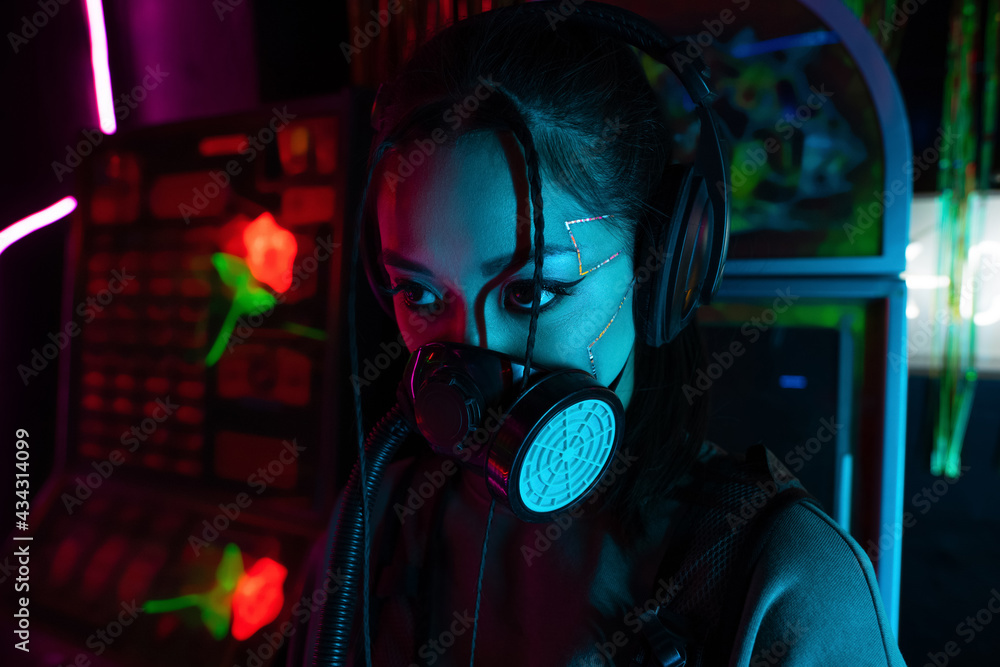 young asian woman with scar in gas mask and wireless headphones looking ...
