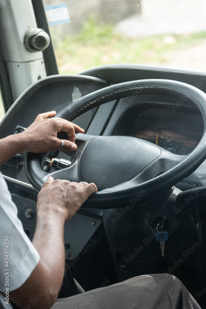 Close-up of a driver's hands holding the steering wheel of a modern bus ...