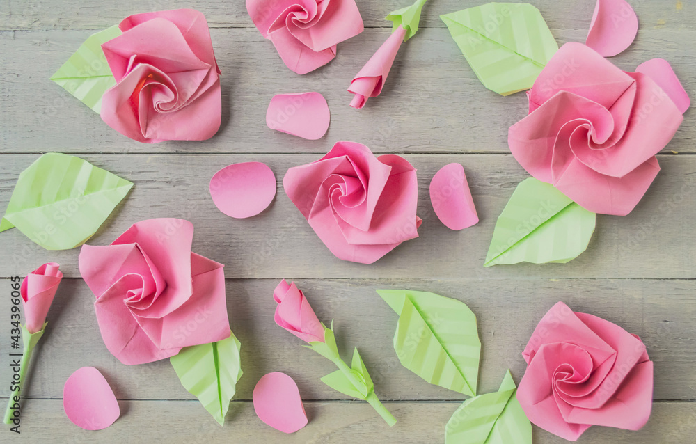 Origami paper background with flowers and leaves. Handmade pink roses ...