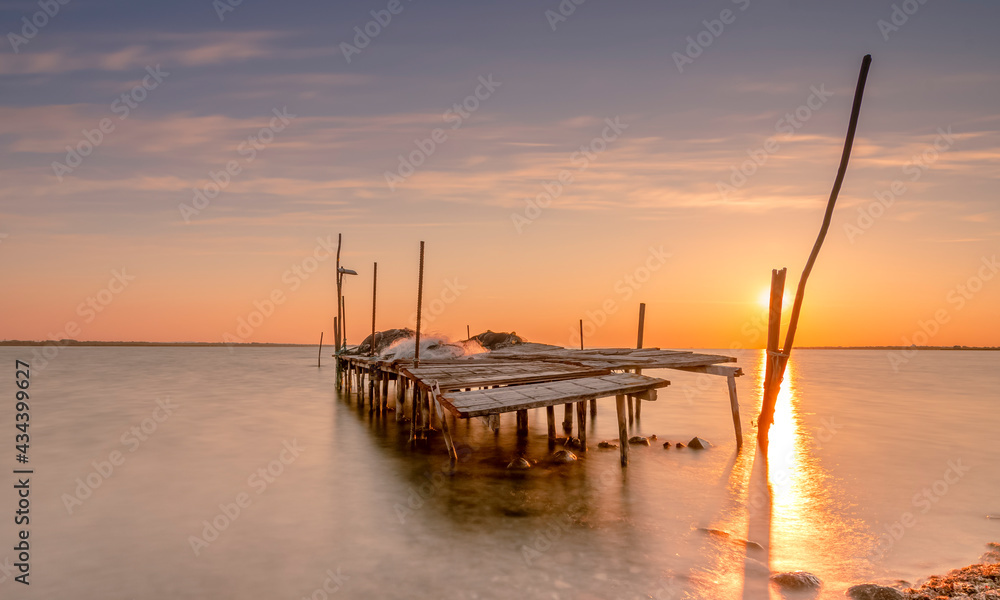 Vue d'un ponton de pêche avec un coucher de soleil sur un étang de la ...