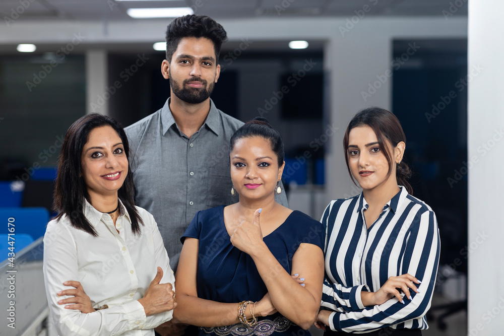 Four Indian office colleagues standing together with arms folded ...