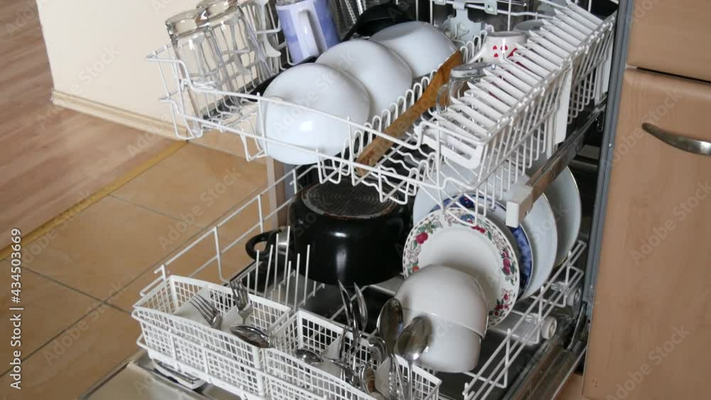 Clean dishes in an open dishwasher after washing. Lots of utensils ...