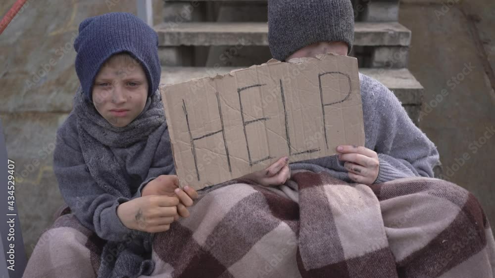 Video Stock homeless boys sit with a help sign on the stairs in an ...