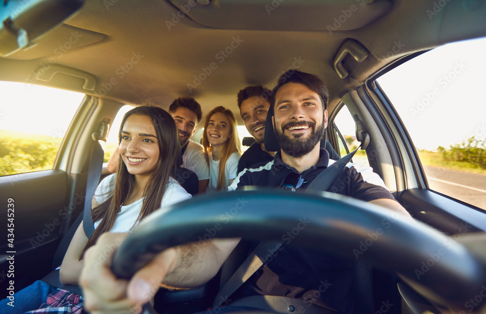 Happy group of people men and women smiling in car, front view. Safety ...