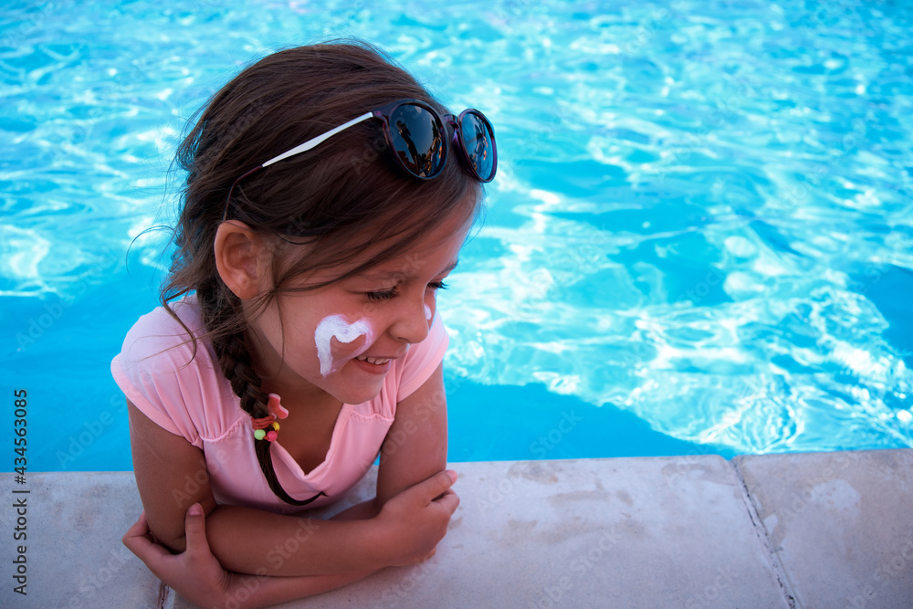 A cute little girl next to the pool with the sun from the cream on her ...