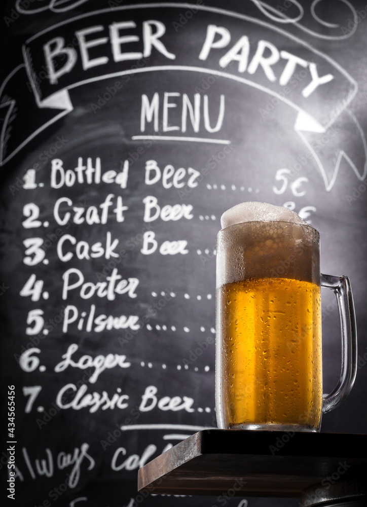 Draft beer in a mug with foam on a bar counter at the chalk board ...