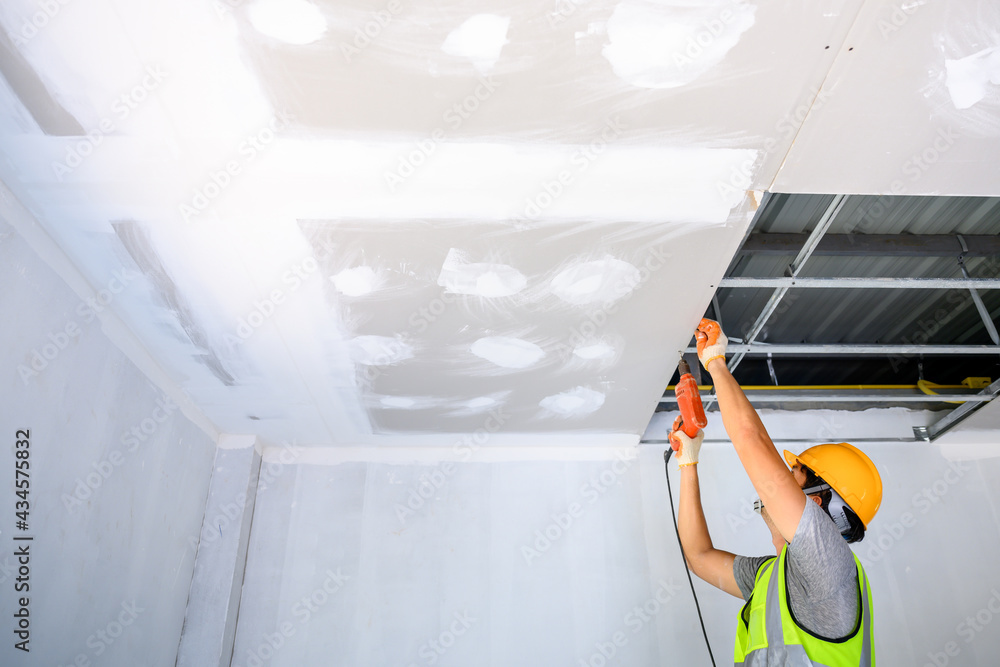 Young male construction workers wearing uniforms Installing gypsum ...