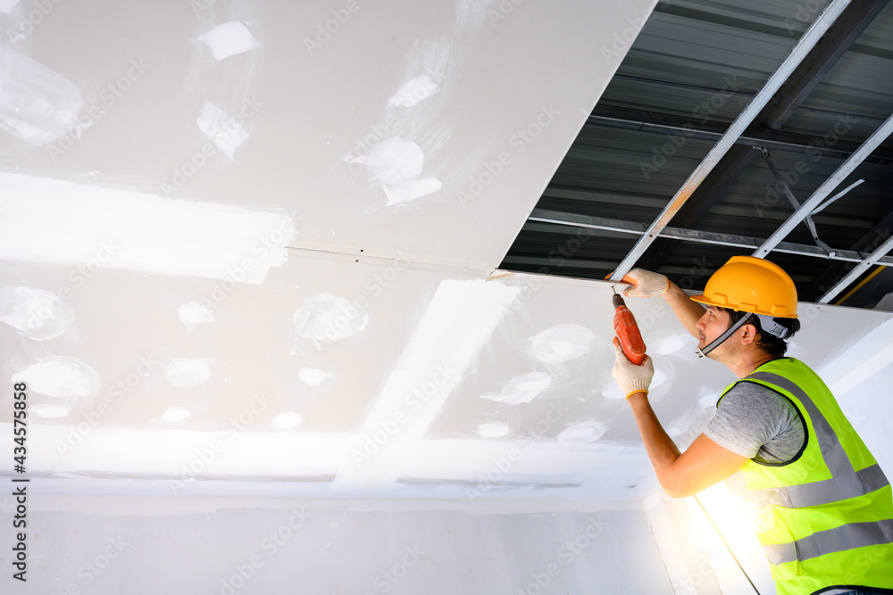 Young male construction workers wearing uniforms Installing gypsum ...