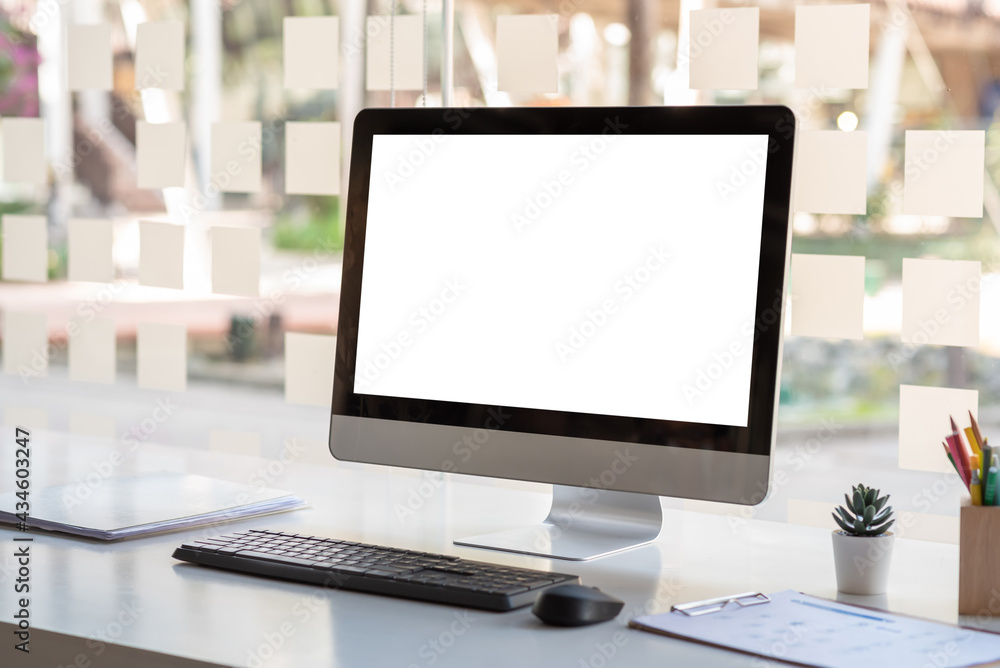 Computer blank white screen with a keyboard and blank papers at the ...