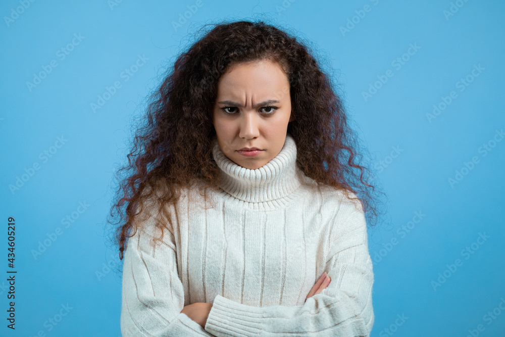 Angry offended woman with curly hair keeping arms crossed and staring ...