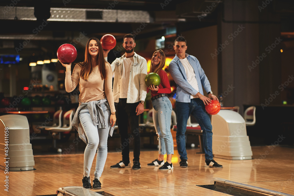Beautiful group of young people posing in a bowling alley with a ball ...