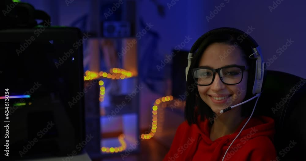 Portrait, happy girl streamer in glasses sits in headphones with a ...