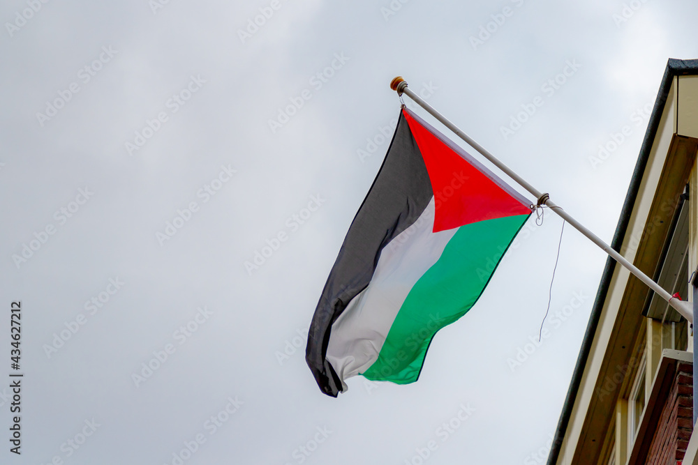 The flag of Palestine hanging outside building and waving on the air ...