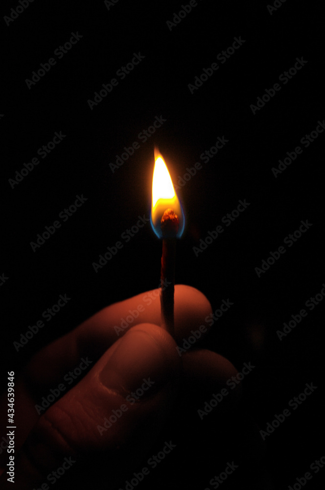 Light of fire from a match while being held by a hand with a black ...