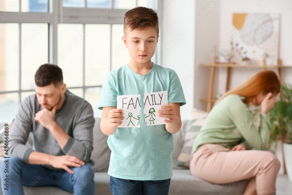 Sad little boy with torn drawing of family after quarrel between his ...