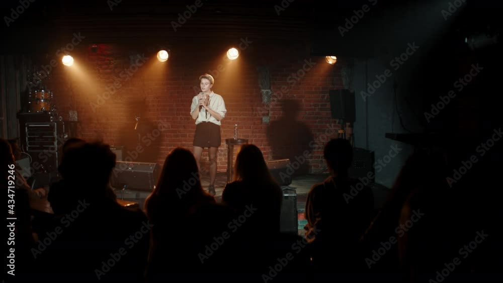Young Caucasian female comedian performing her stand-up monologue on a ...