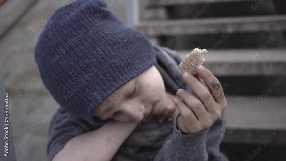 Video „homeless boy sits on stairs in bandoned place holding bread in ...