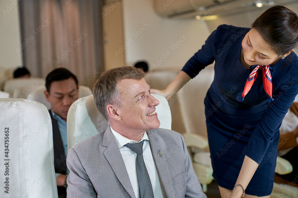 Air hostess help a businessman change position of the seat before ...