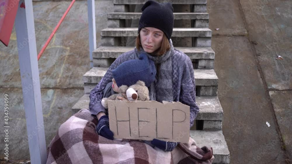 homeless mother with a child with a sign Help on the stairs in an ...