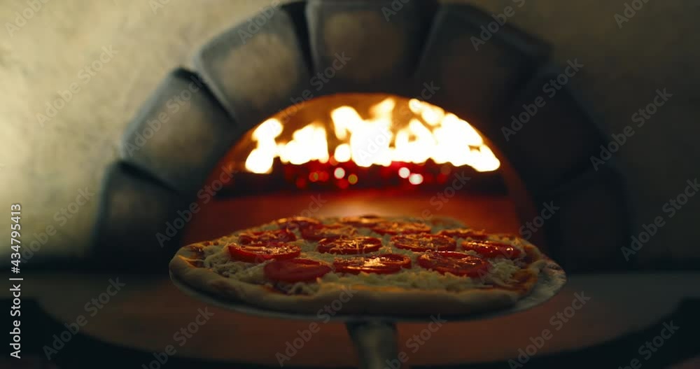 POV bakery worker putting Italian pizza with tomatos in stone oven with ...