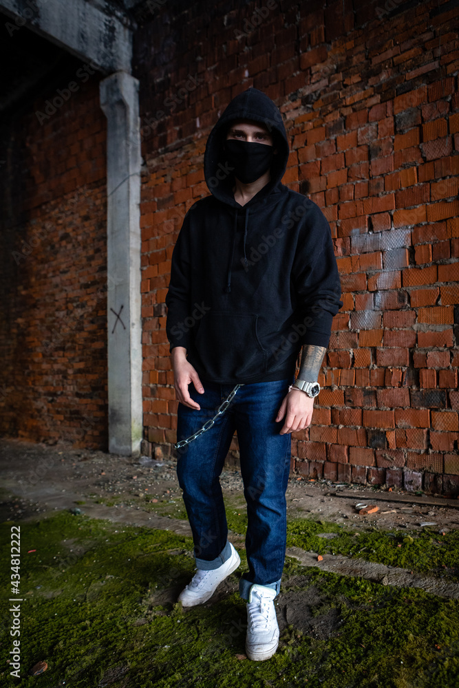 Young handsome criminal gangster model man in a black mask against ...