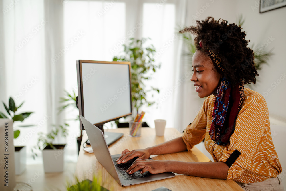 Beautiful African American girl is using laptop and looking and screen ...