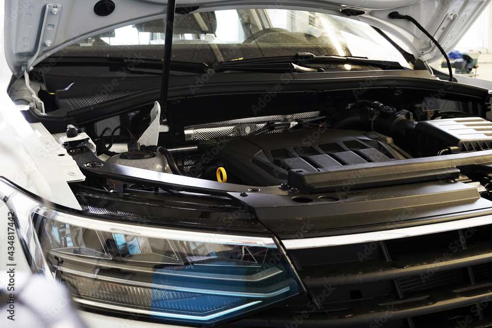 On a modern car, the hood is open and the engine is visible. Car ...