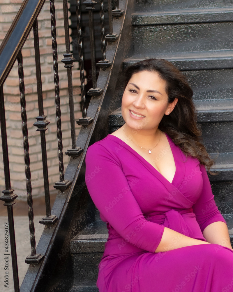 Beautiful Latin Mexican woman on a purple pink dress sitting on a ...