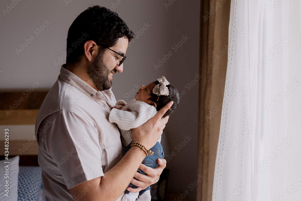Young hispanic father holding his newborn baby at home - New father ...