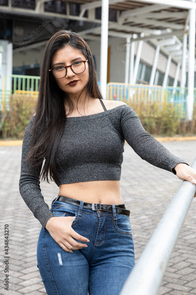 slim latin woman with long black hair, standing and leaning against the ...