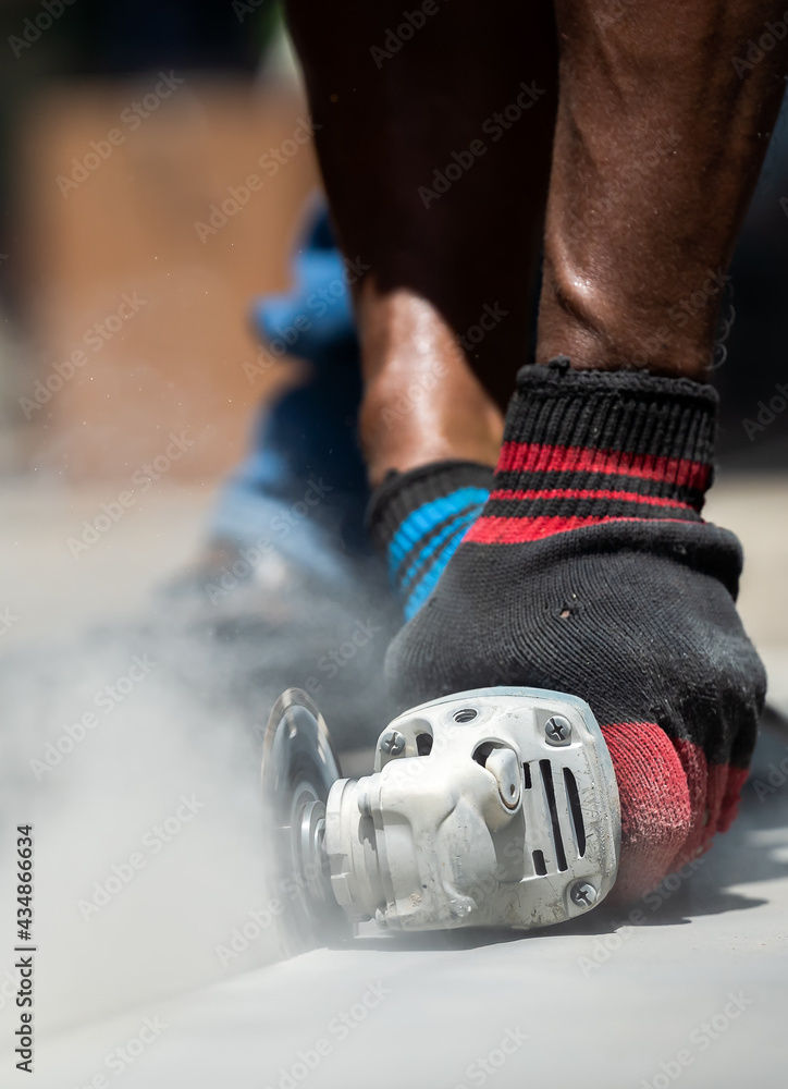 Worker in gloves with a small angle grinder cuts fibre cement, concrete ...