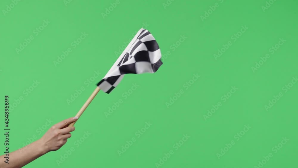 Female hand holding and waving checkered race flag in slow motion against green screen ...