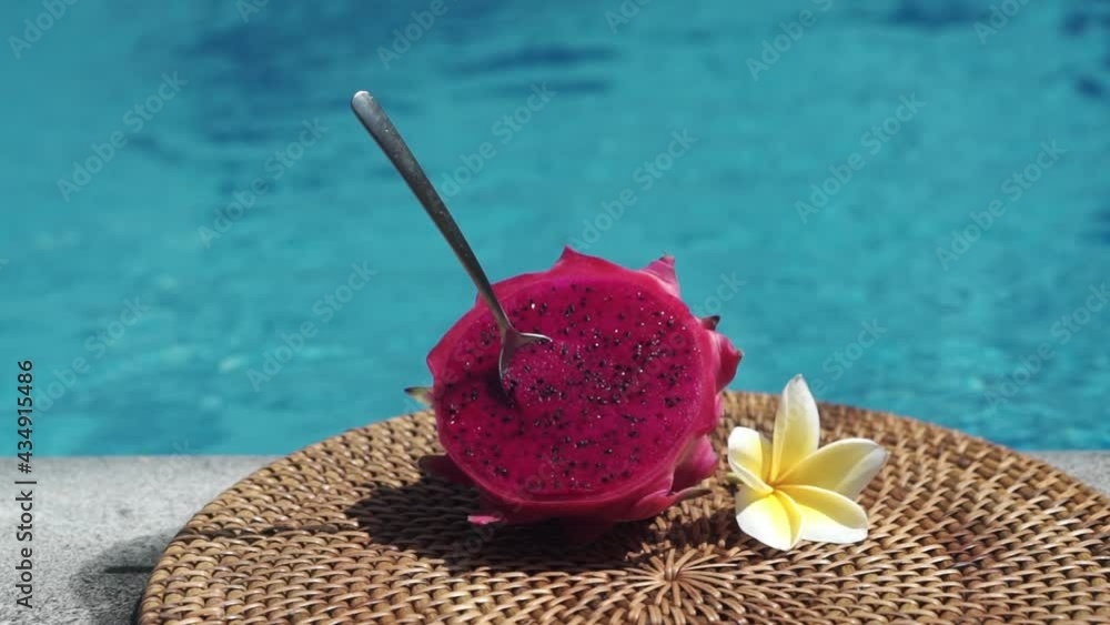 Fresh red dragon fruit cut into two halves with a spoon stuck into the ...