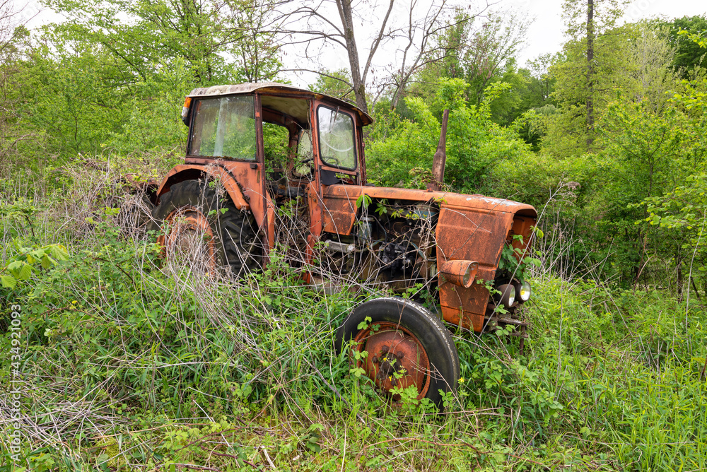 Old rusty vintage abandoned tractor in a field overgrown with tall ...