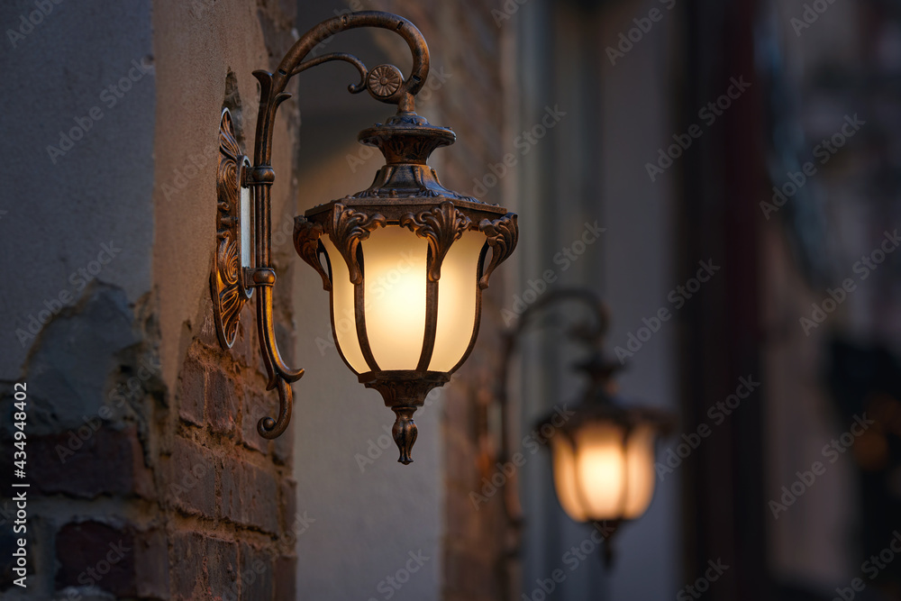 Old street lantern lighting on facade of building. Twilight on city ...
