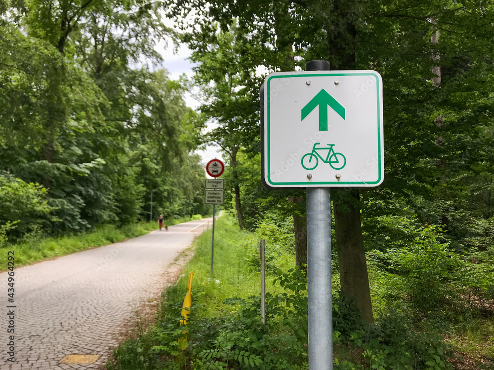 White-green bikeway sign with a straight arrow on a metal pile beside a ...