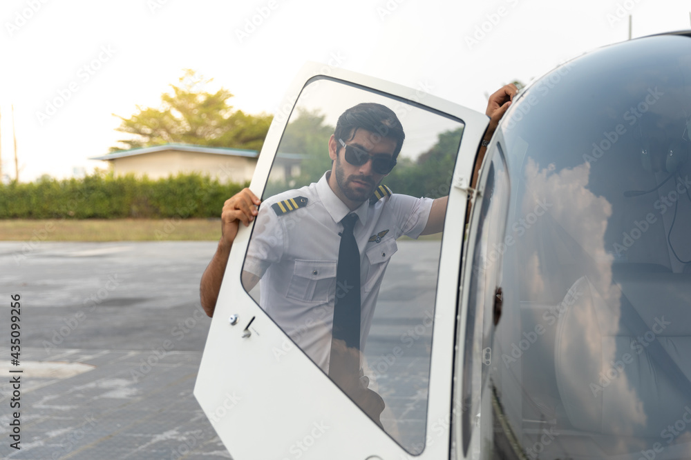 Young male pilot standing next to his helicopter ready to take off. He ...